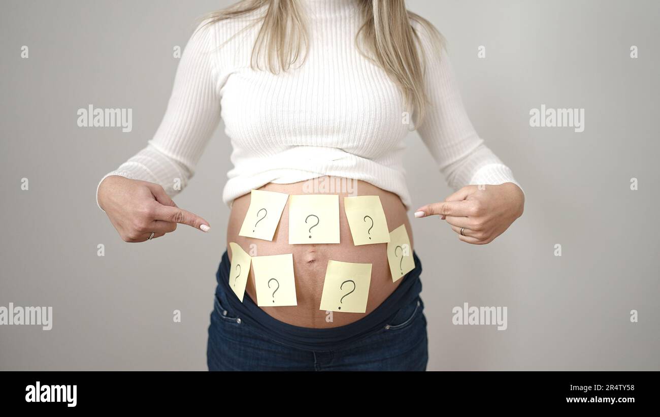 Young pregnant woman pointing to question marks reminder papers on ...