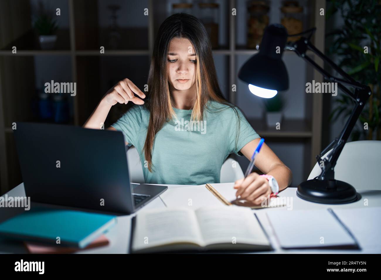 Teenager girl doing homework at home late at night pointing down ...
