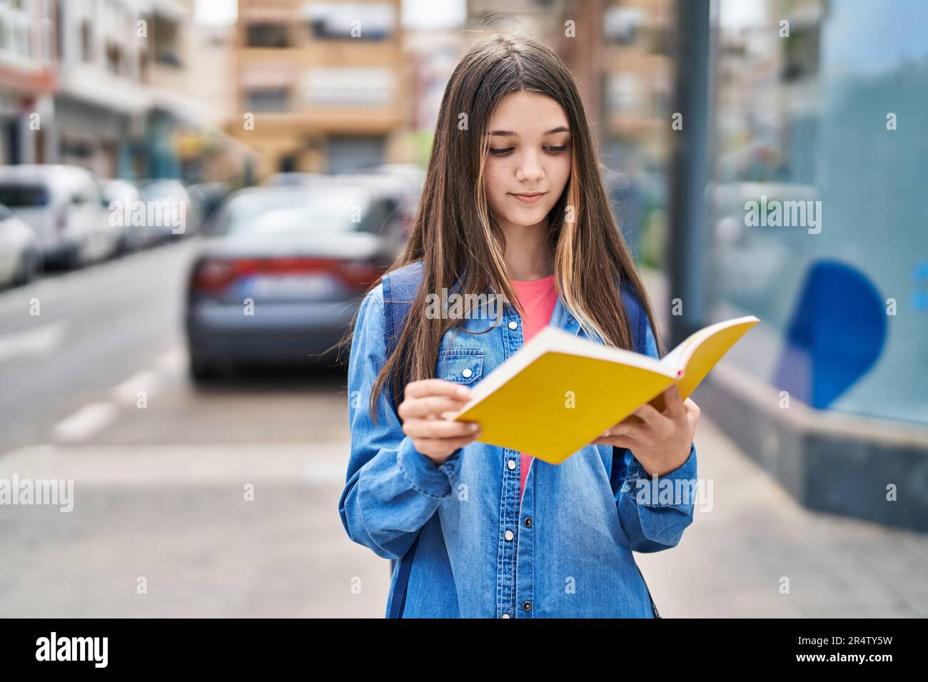 Adorable girl student reading book standing at street Stock Photo - Alamy