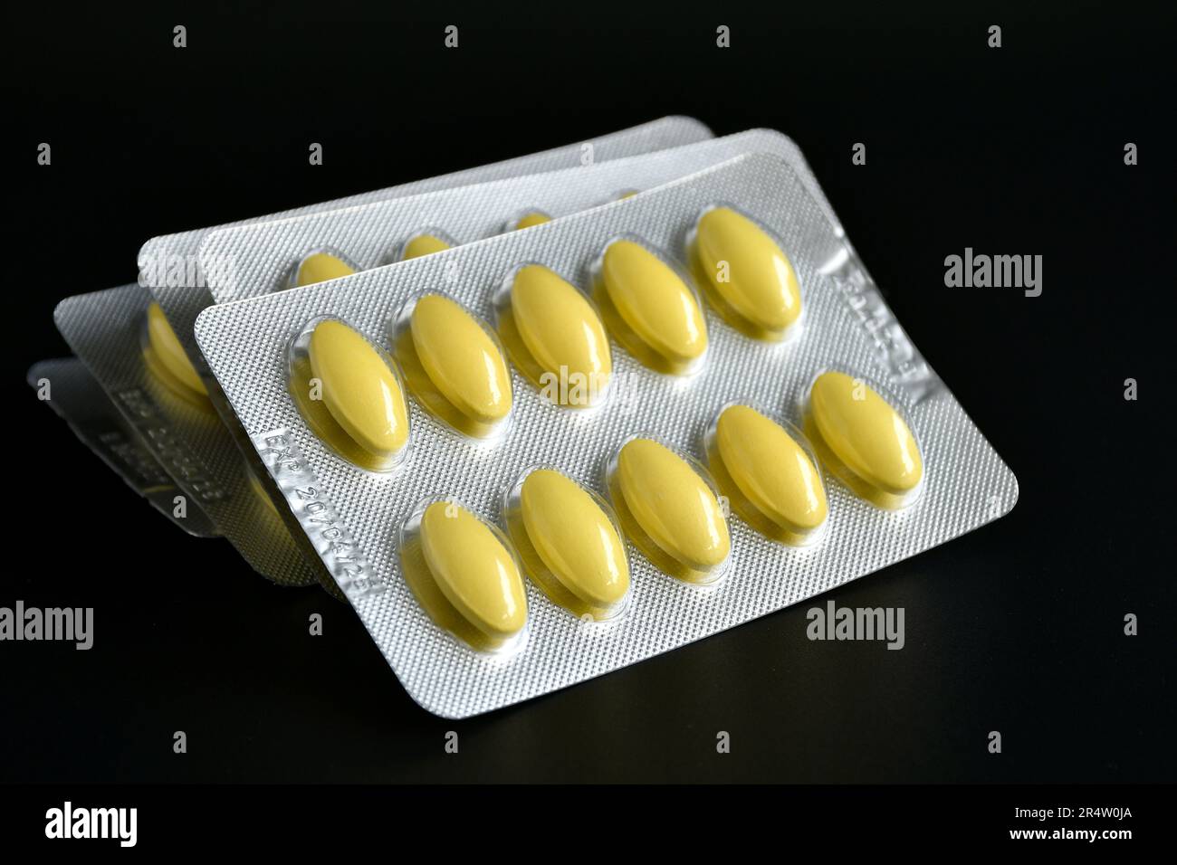 Yellow coated compress tablet in blister pack isolated on black ...
