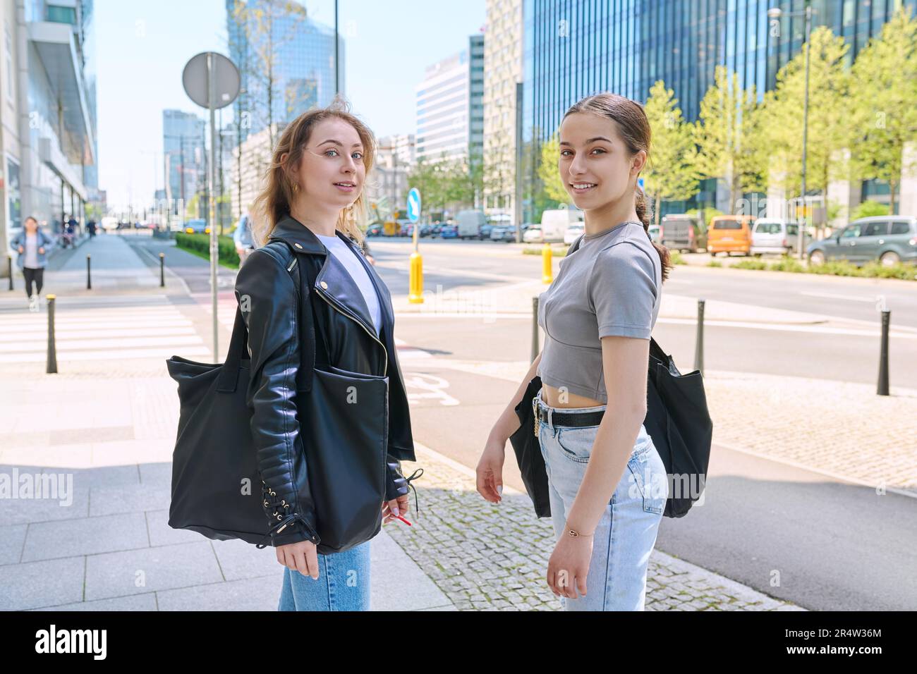 Two smiling female students looking at camera, urban modern background ...