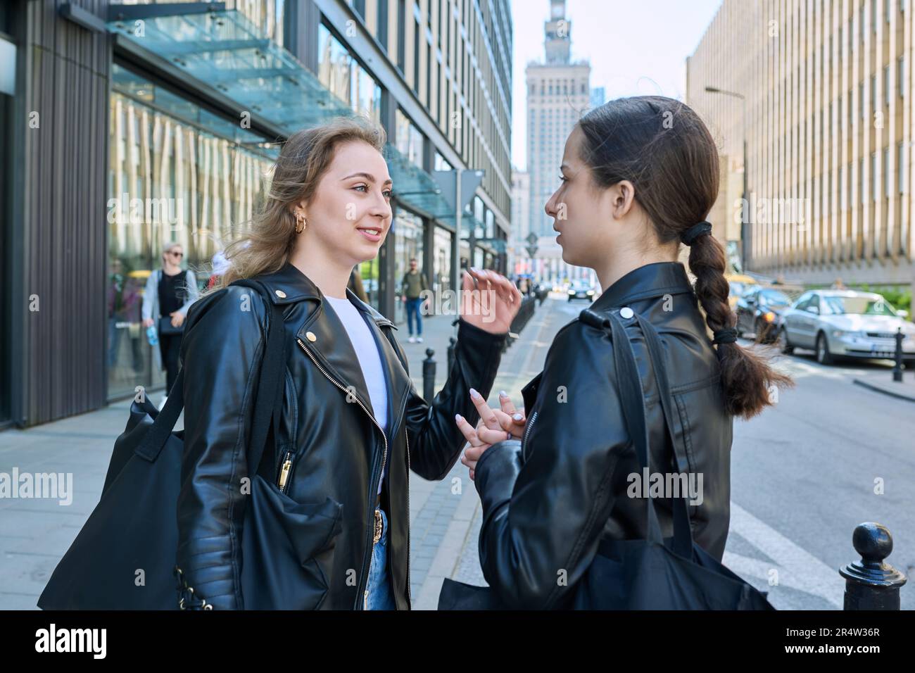 Two young female talking on street of city Stock Photo - Alamy