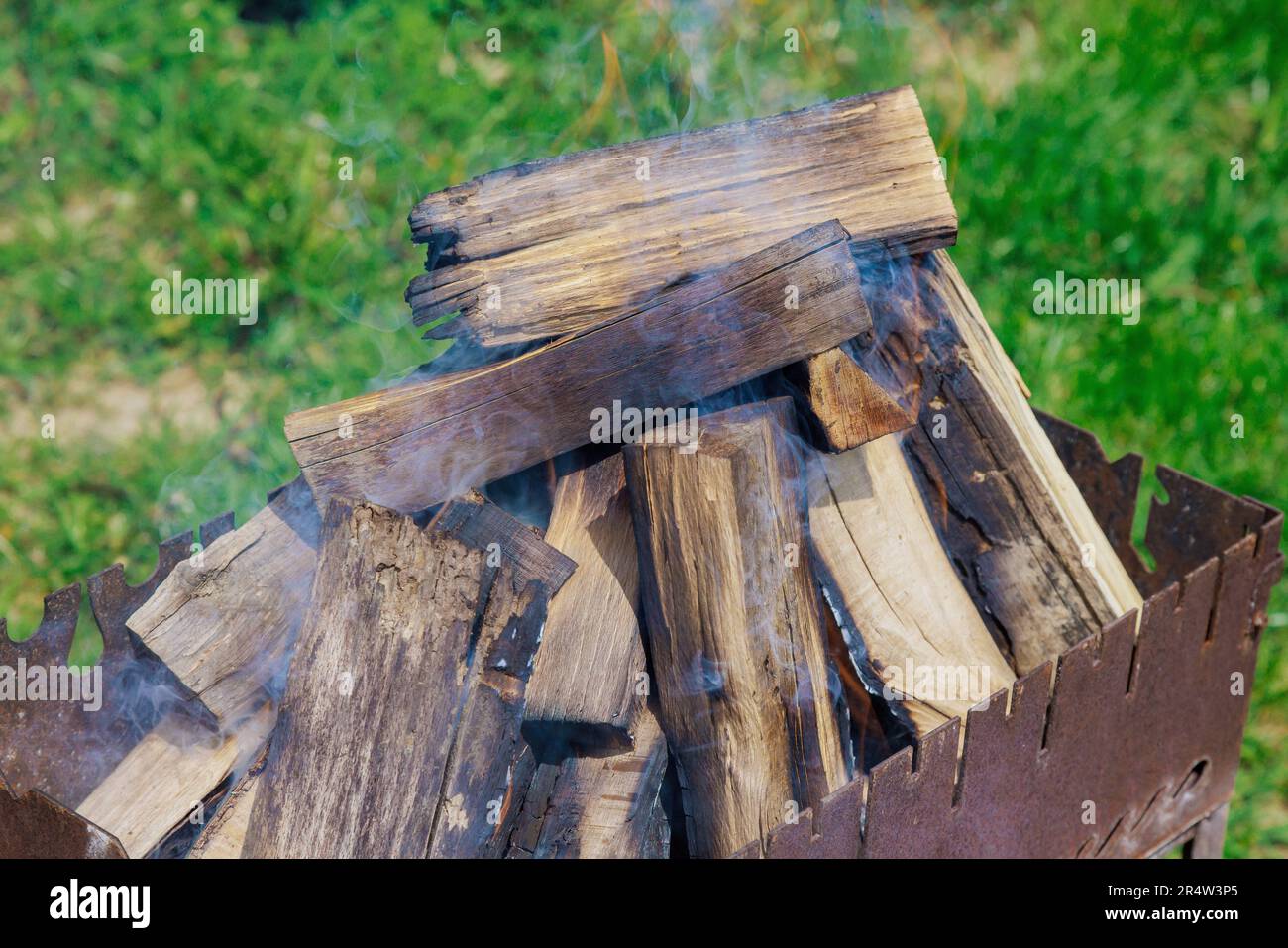 Small folding portable brazier filled with burning wood in the BBQ ...