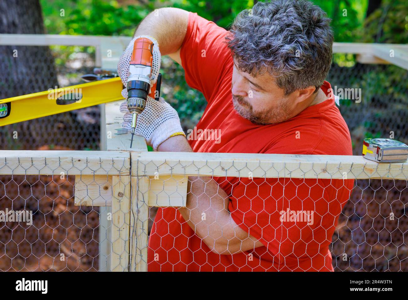 Worker uses screwdriver to wooden domestic chicken coop on farm that ...