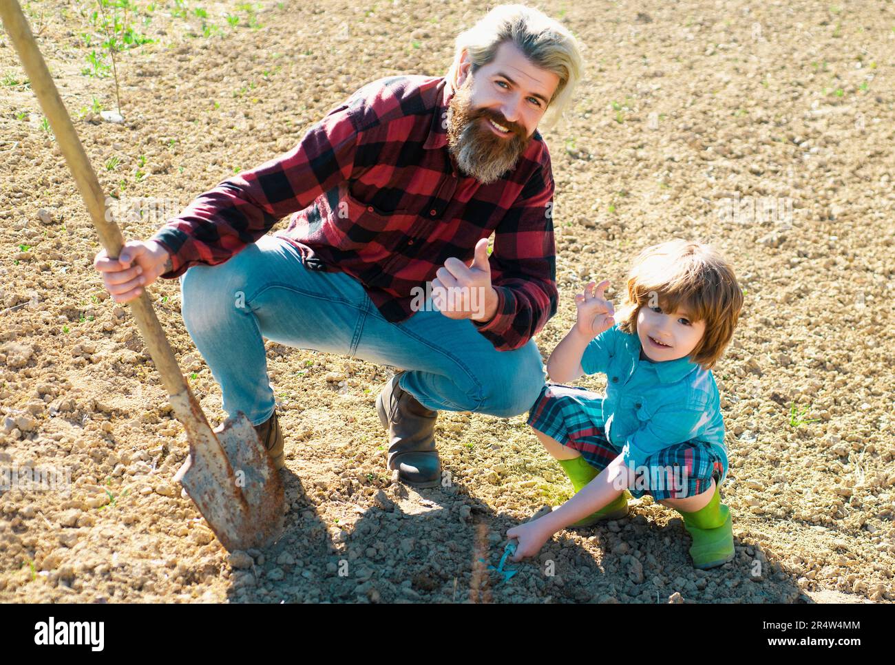Father planting with helper son. Dad and kid gardening in garden ground ...