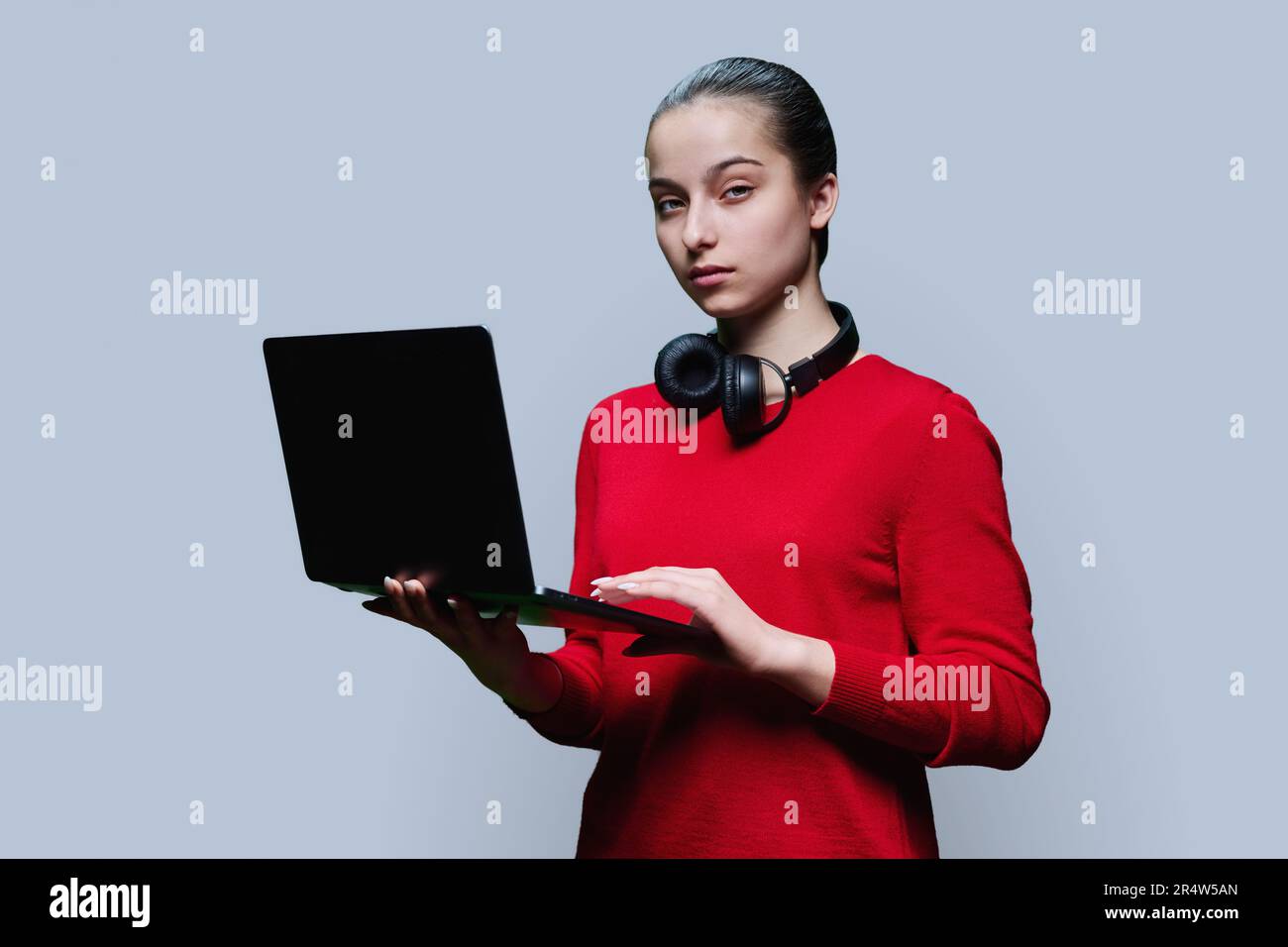 Teenage girl high school student using laptop on grey background Stock ...