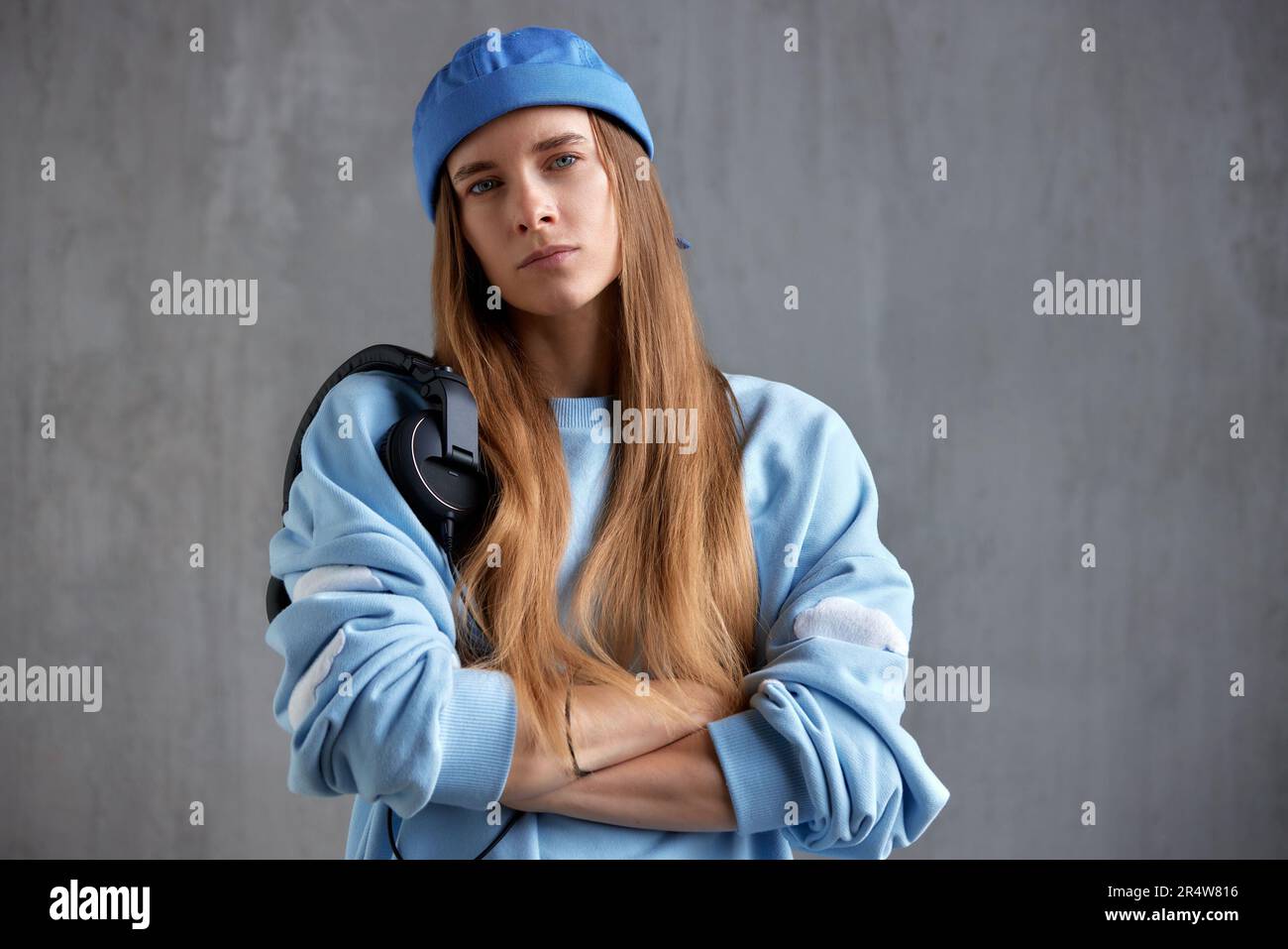 A young pretty long-haired girl in a blue sweater and a funny hat with ...