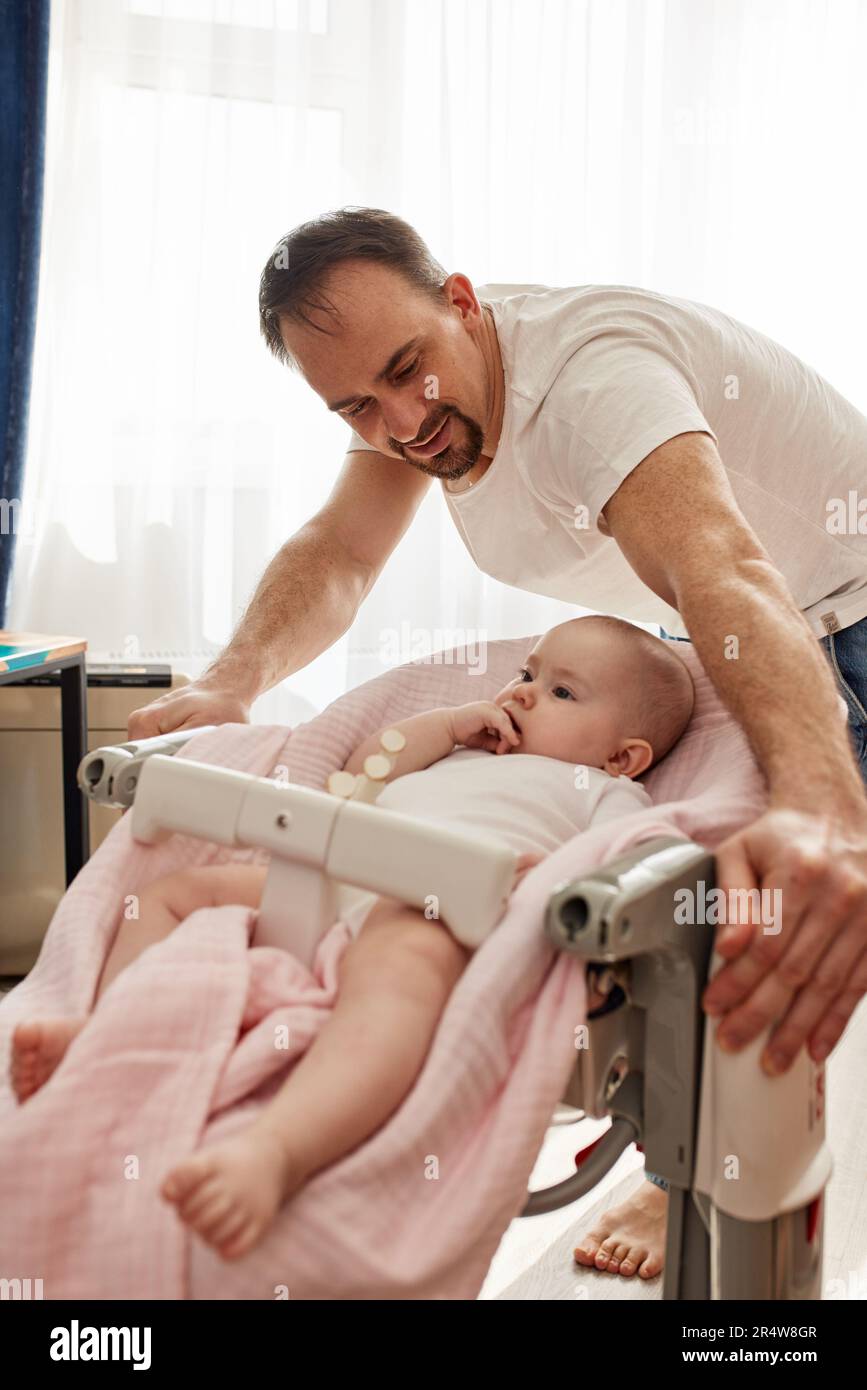 A happy smiling father holds a child seat in which his beloved baby ...