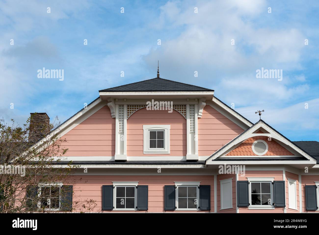 A multi-story pink-painted wooden Victorian style house with white trim ...