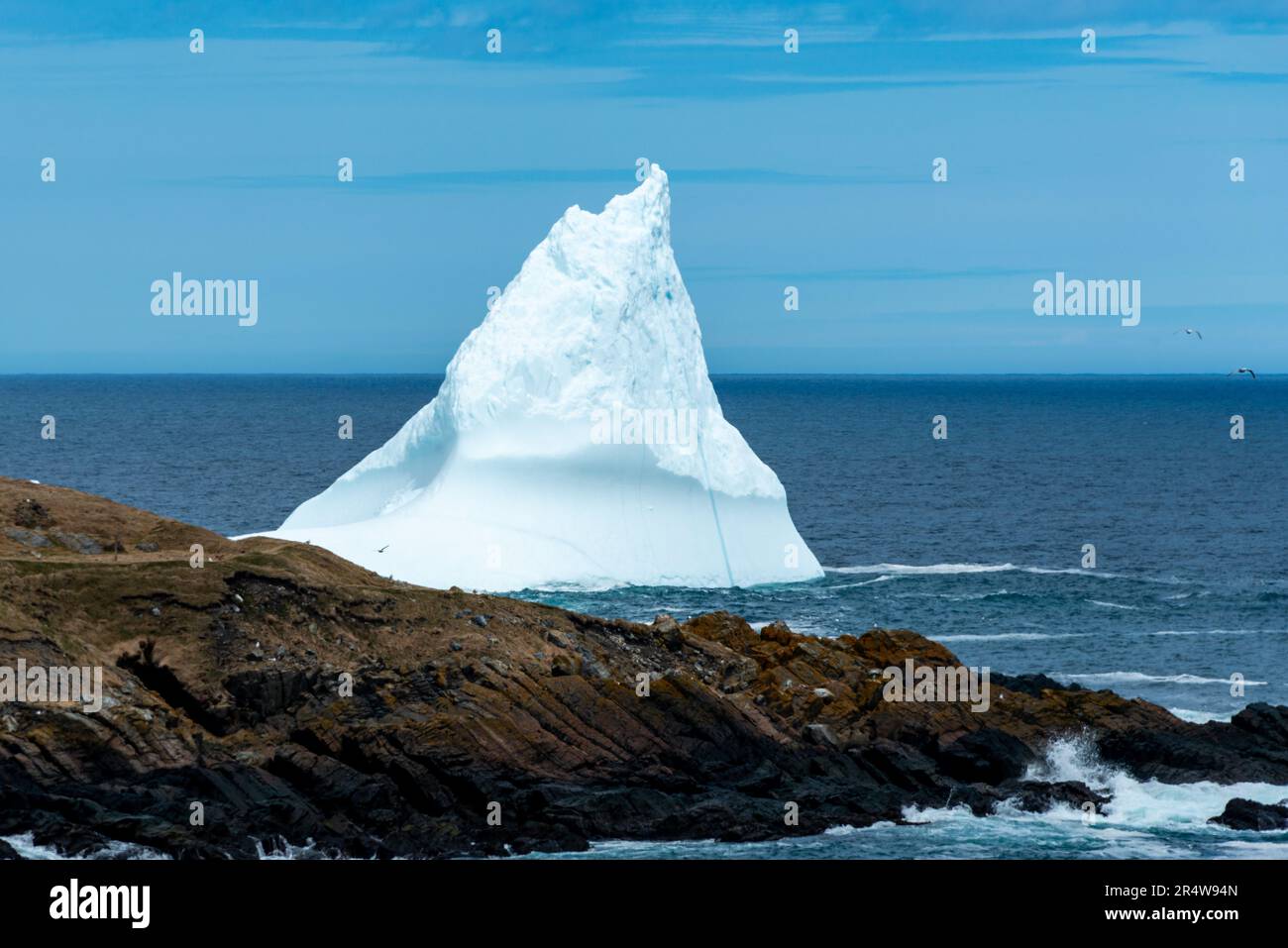 A large white iceberg formation floating in the cold ocean with layers ...