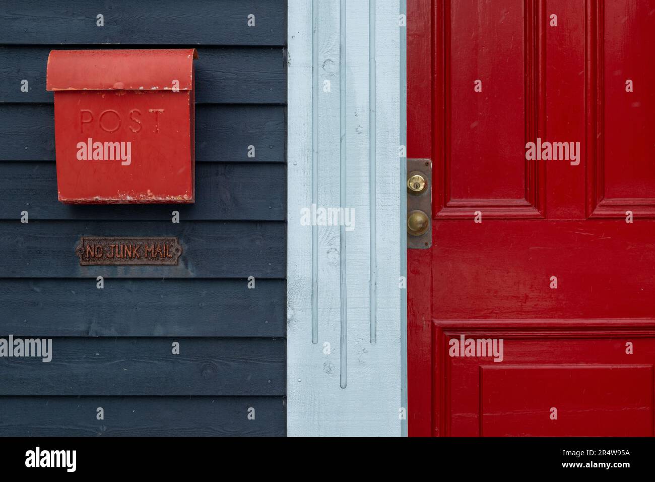 A bright red metal mailbox or letterbox on a deep blue wooden wall with ...