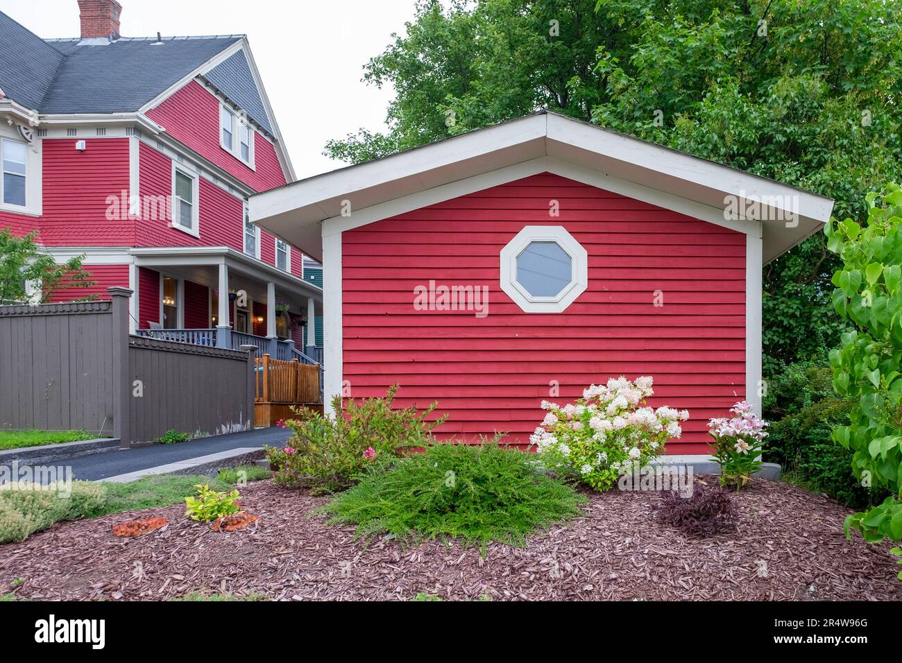 A vibrant red wooden shed with white trim in a backyard of a country ...