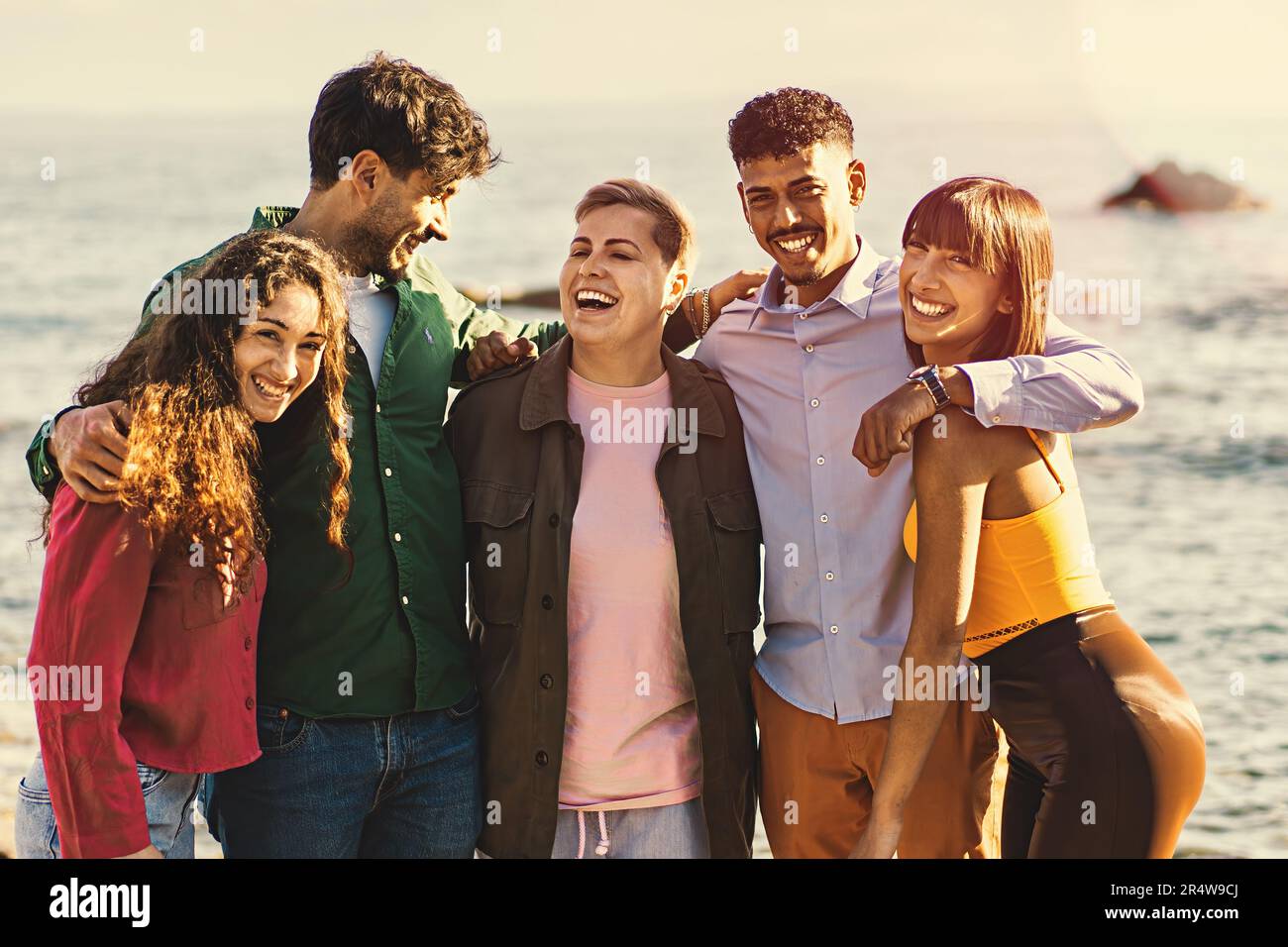 Group of multi-ethnic friends walking seaside, sharing a light-hearted ...