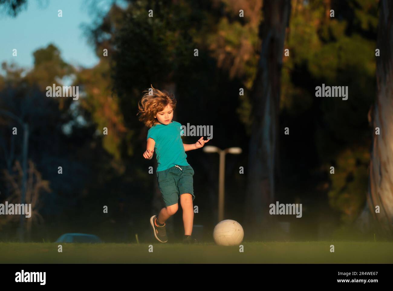 Little kid boy playing football in the field with soccer ball. Concept ...