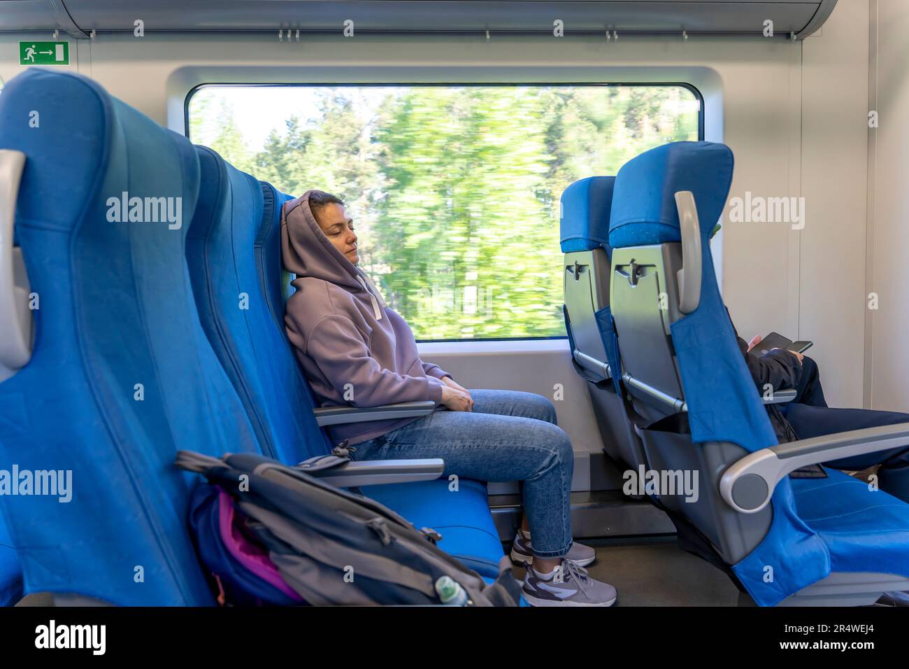 a pretty middle-aged woman sleeps sitting in a commuter train chair ...
