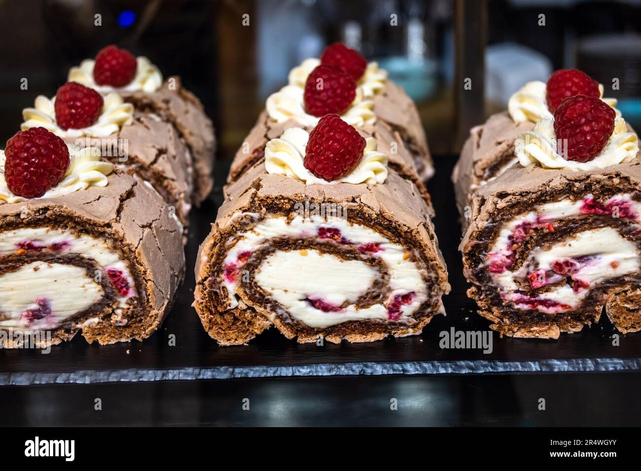 Sweet cake, roulade with cream, cocoa and raspberry on glass shelf ...