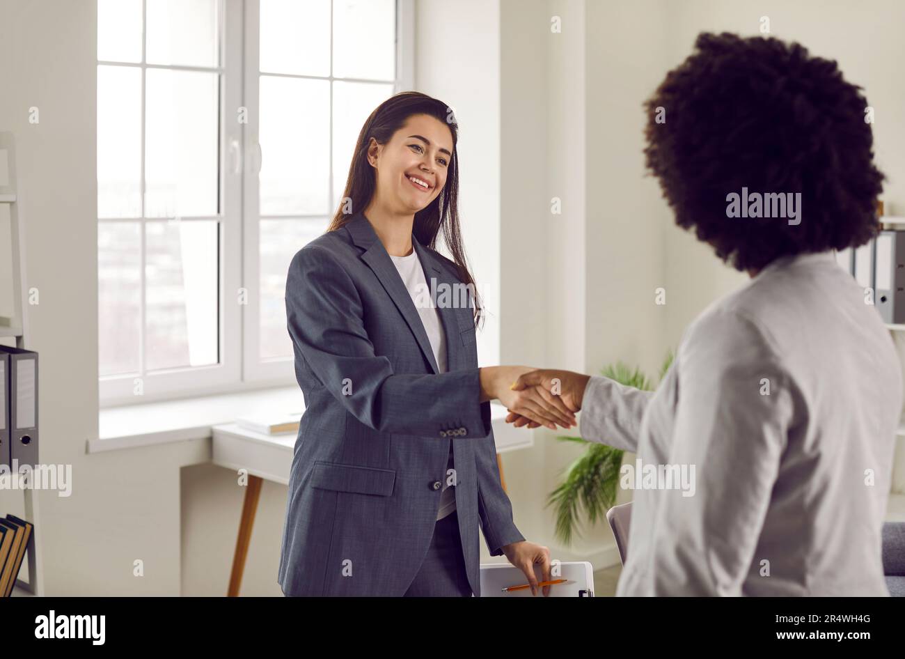 Two happy young business women meet in the office, smile and exchange handshakes Stock Photo - Alamy