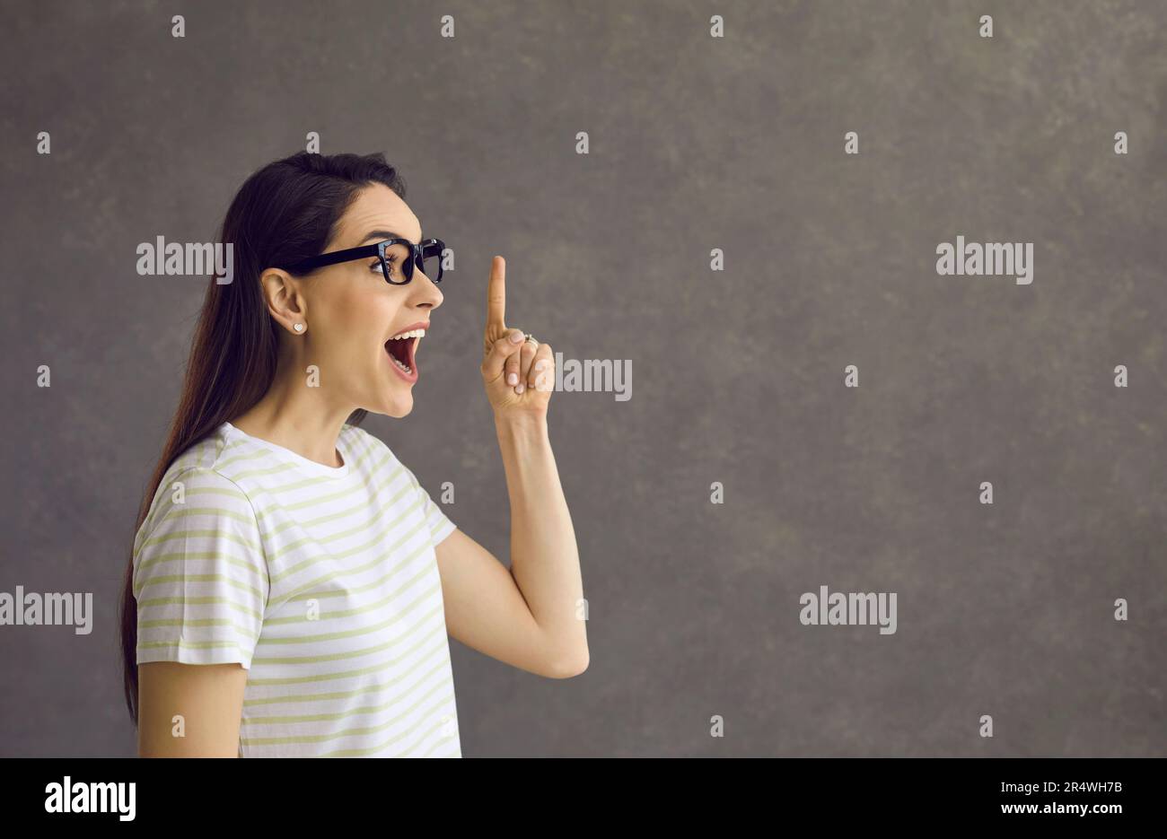 Smart woman with eyeglasses showing aha emotion on face pointing finger ...
