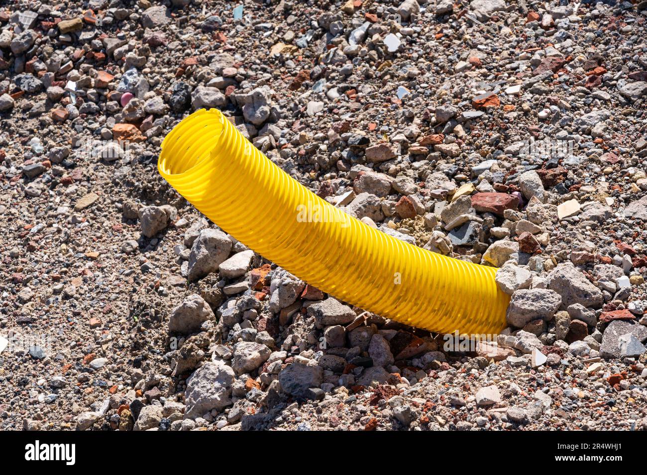 Yellow corrugated pipe sticking out of the ground covered with stones ...