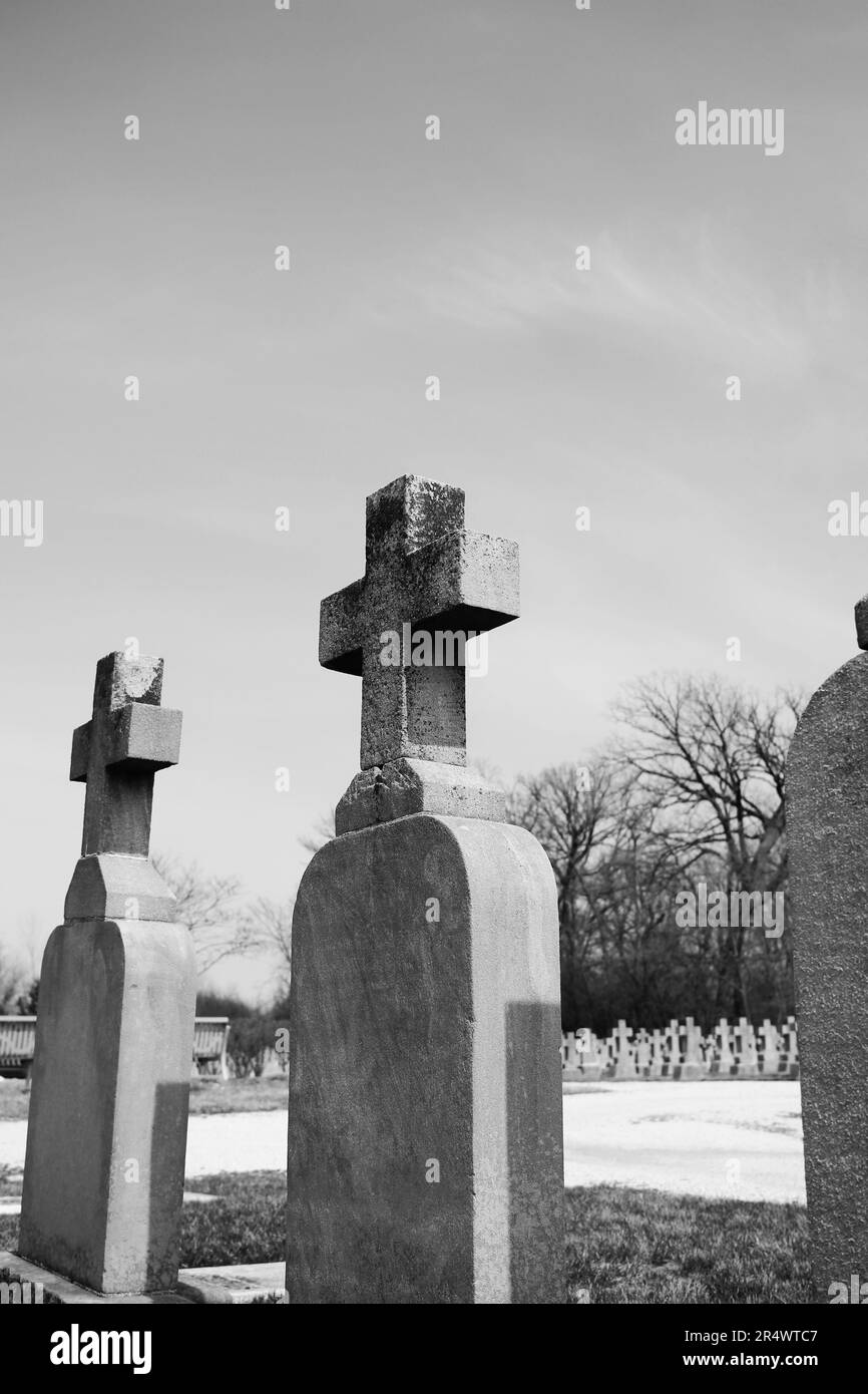 Simple plain stone cross standing in the sunny cemetery in a black and ...