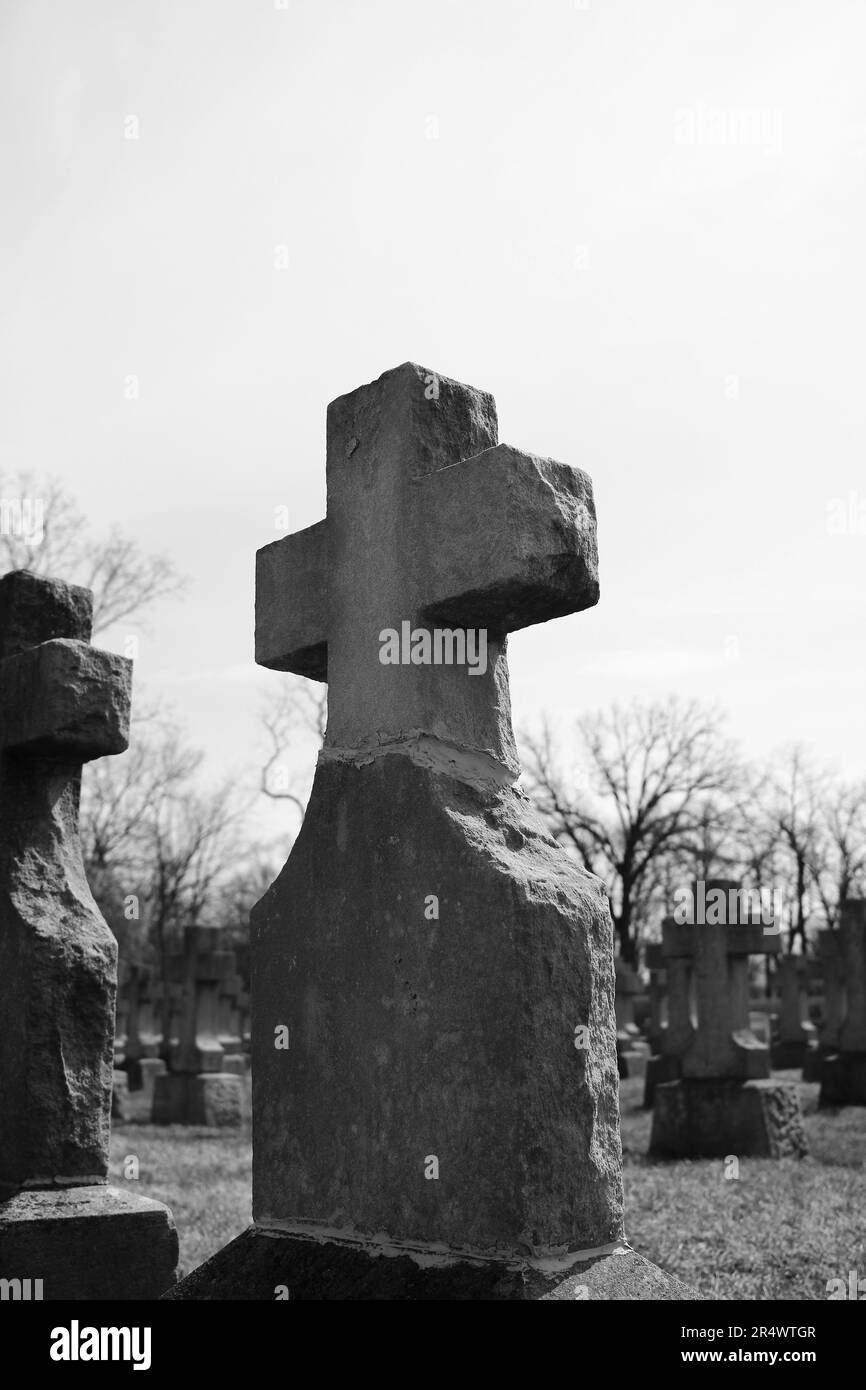 Simple plain stone cross standing in the sunny cemetery in a black and ...