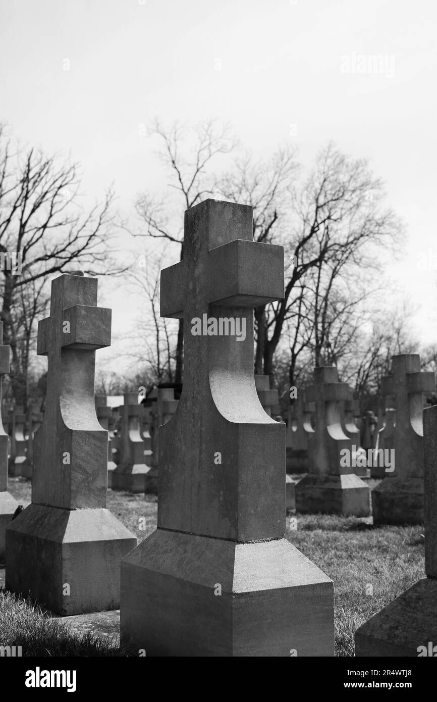 Simple plain stone cross standing in the sunny cemetery in a black and ...