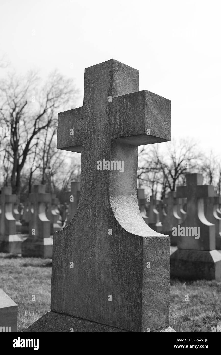 Simple plain stone cross standing in the sunny cemetery in a black and ...