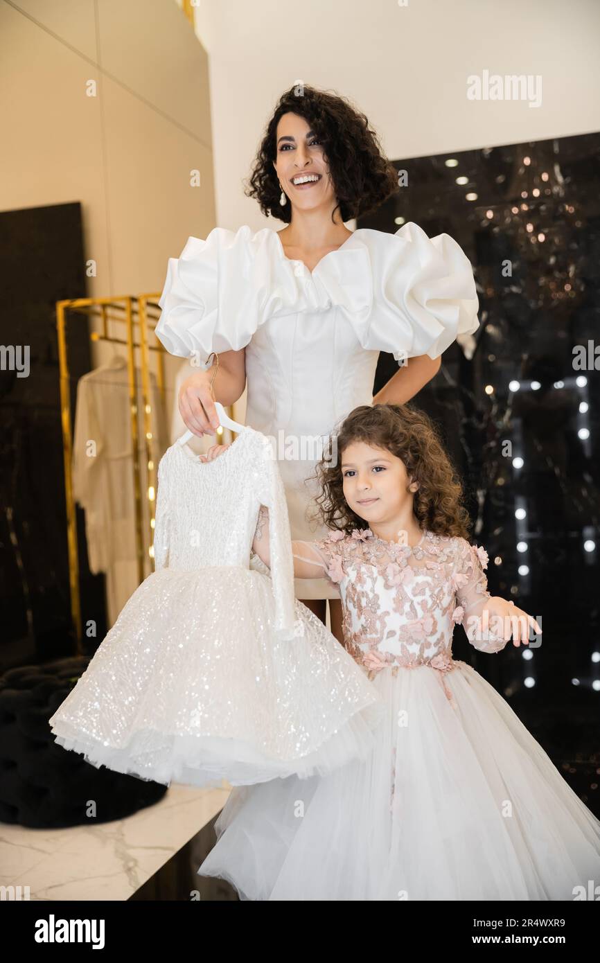 charming middle eastern bride with brunette hair standing in white ...