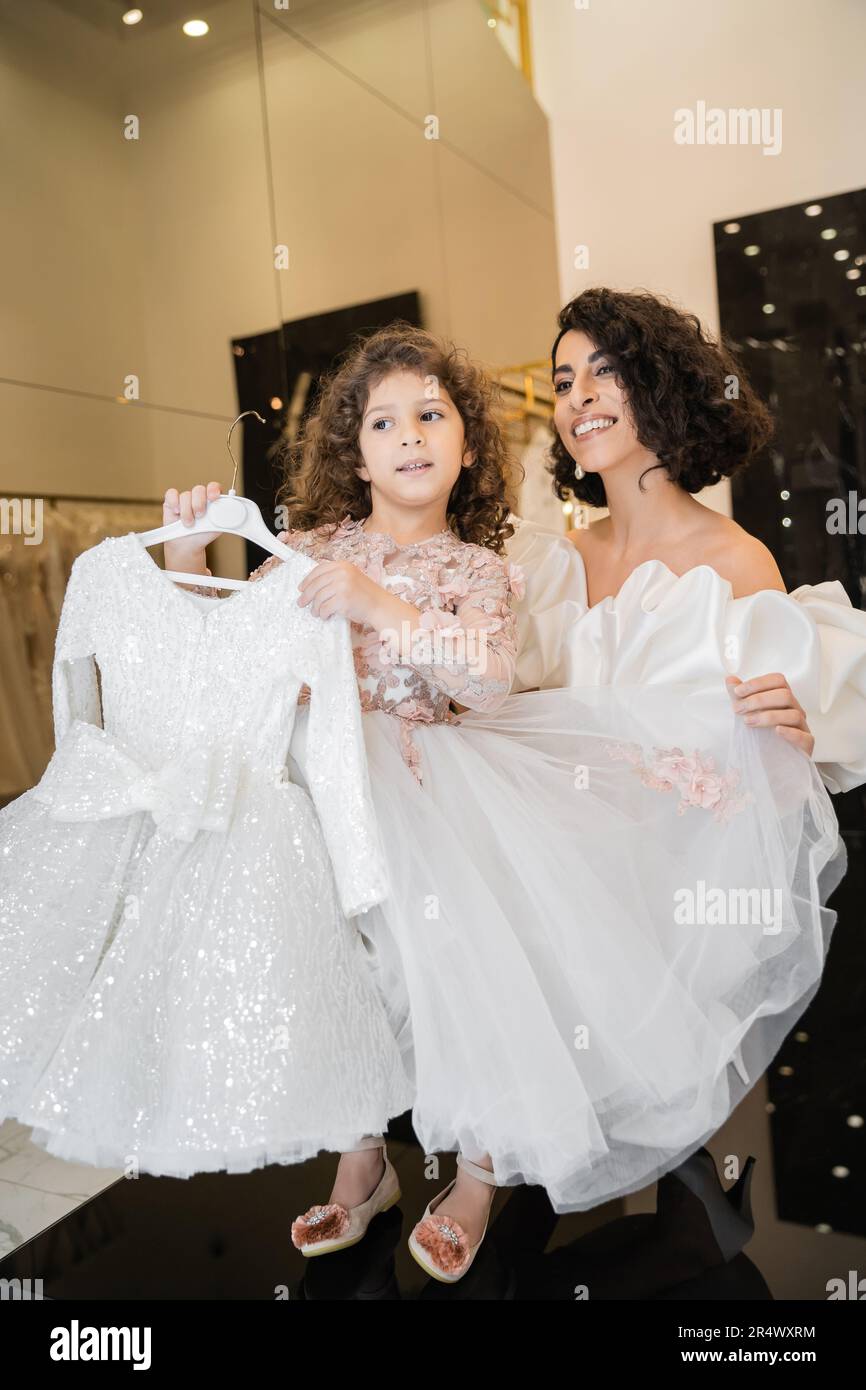 charming middle eastern bride with brunette hair standing in white ...