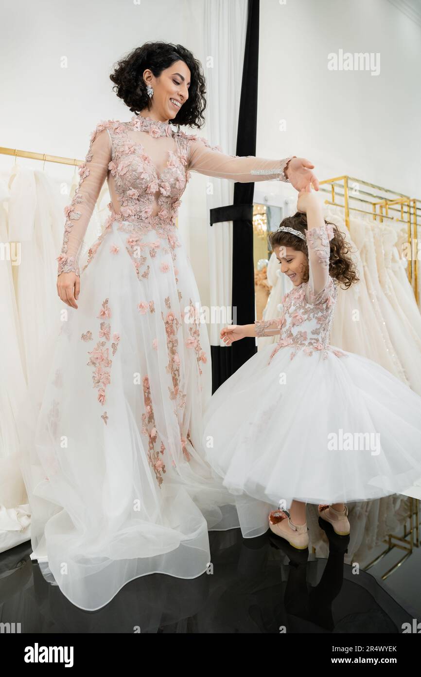 happy middle eastern woman in floral wedding dress dancing with smiling ...