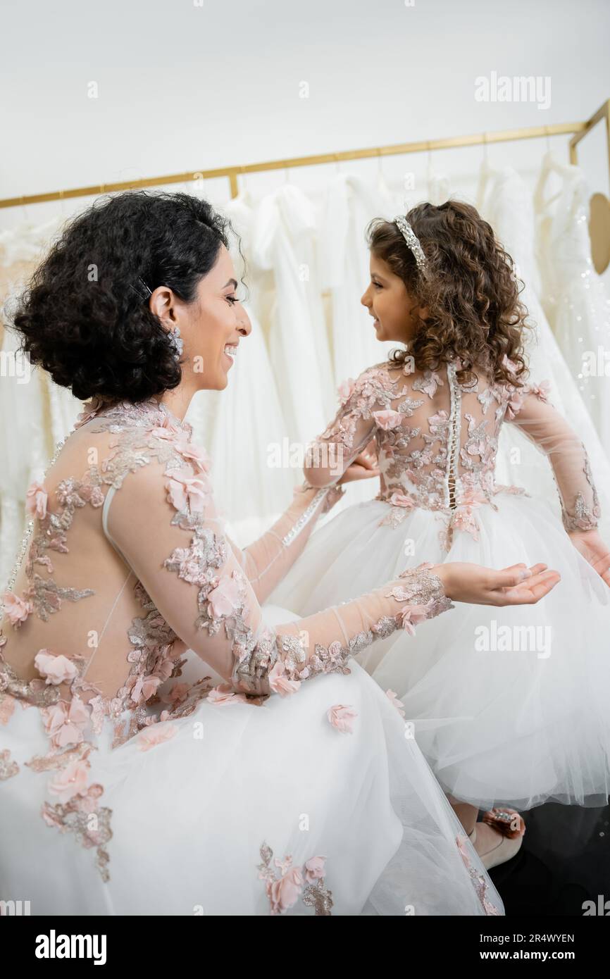 happy middle eastern woman with brunette wavy hair in floral wedding ...