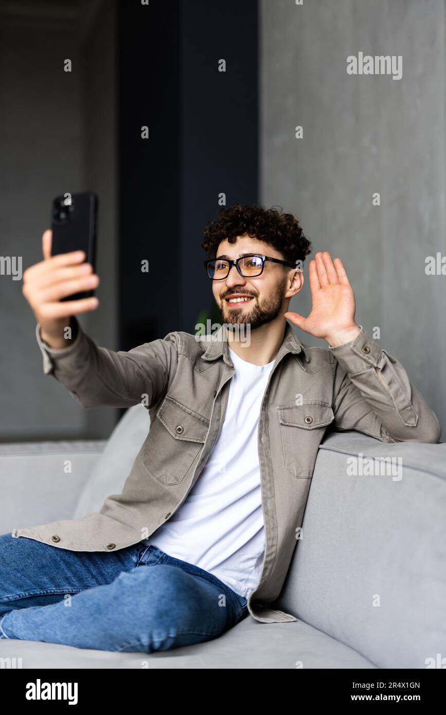 Online video call. Positive man waving hand to webcam, having pleasant ...