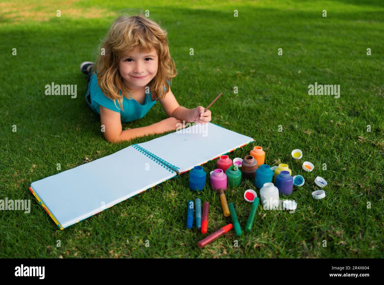 Children creative, developing imagination, creativity. Child boy drawing in summer park ...
