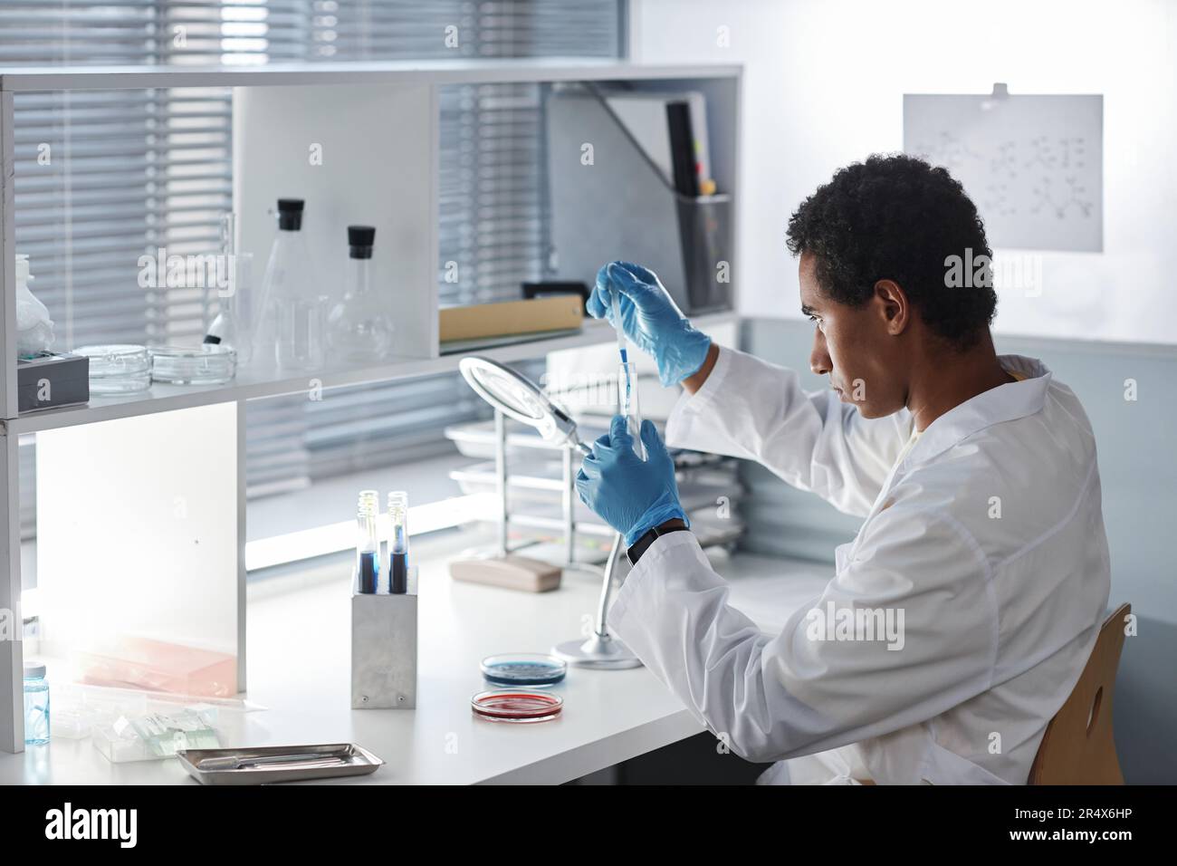 Side view portrait of ethnic young man doing tests at workstation in ...