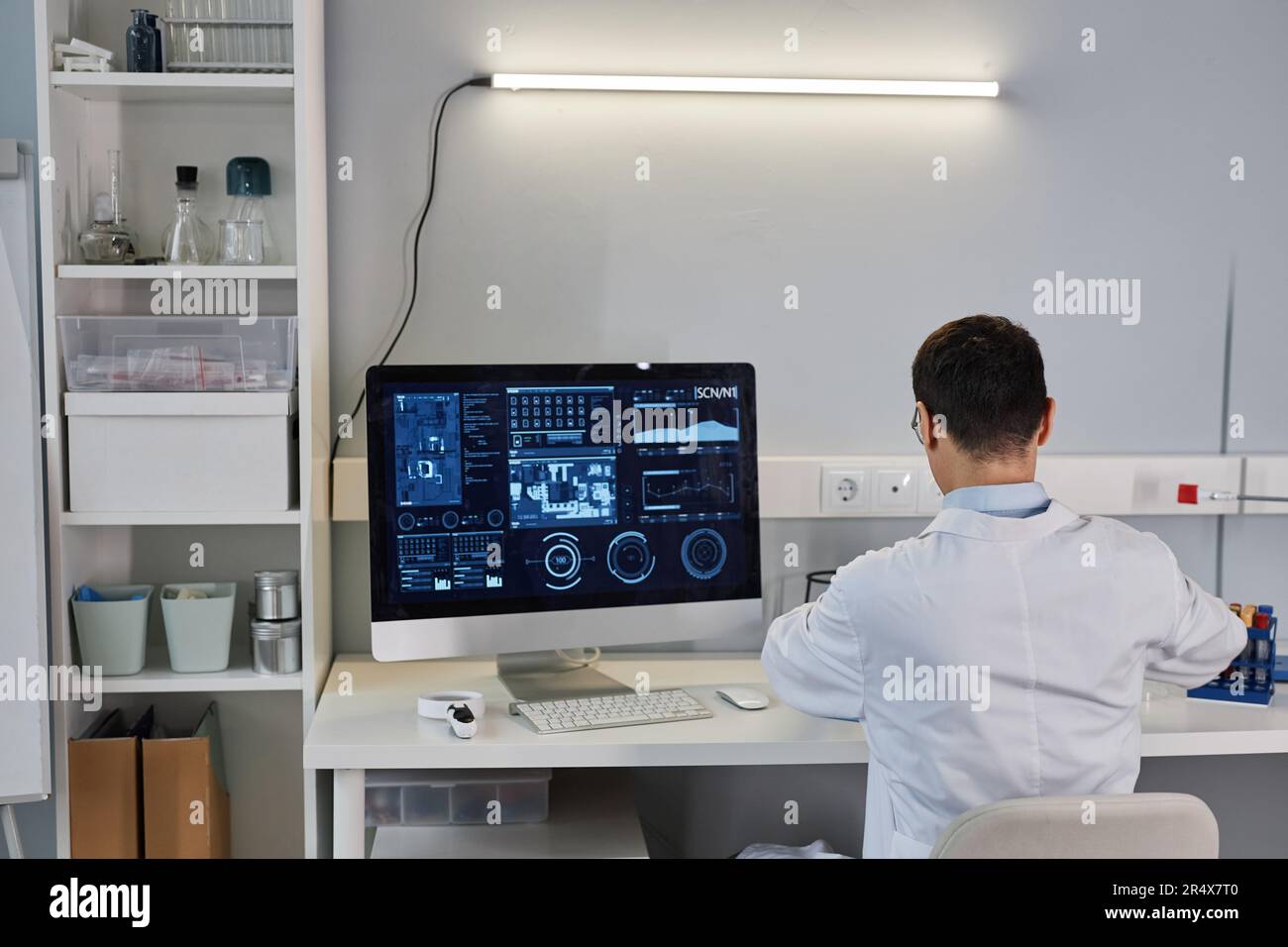 Back view at male scientist at desk in laboratory analyzing scientific ...