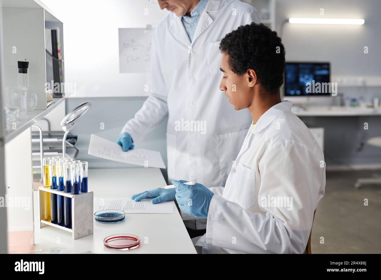 Side view portrait of two scientists working with documents in ...