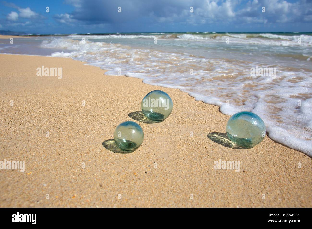 Three, glass Japanese fishing balls (floats) on the wet sand of the ...