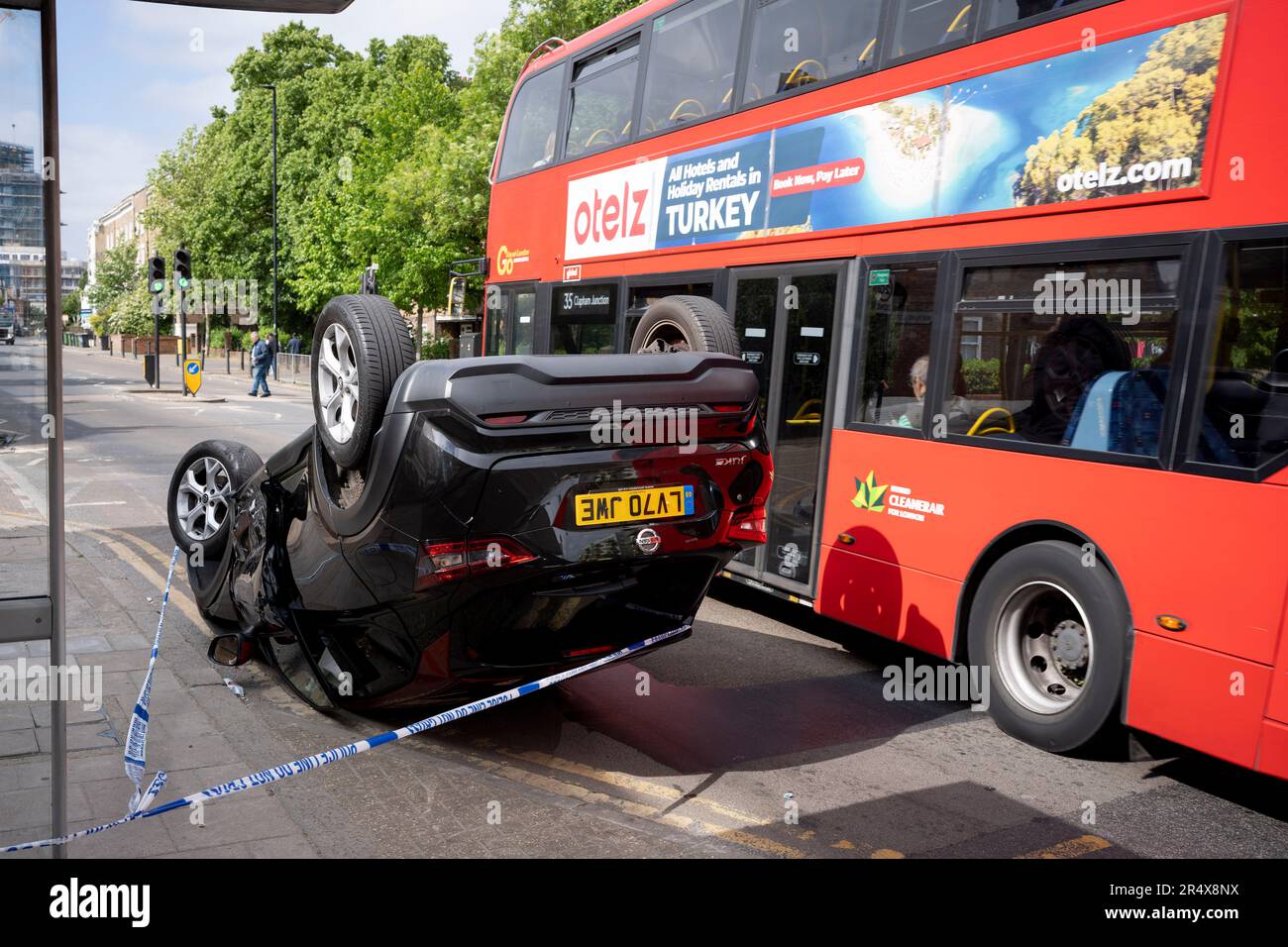 A London bus passes the aftermath of a car crash in which an overturned ...