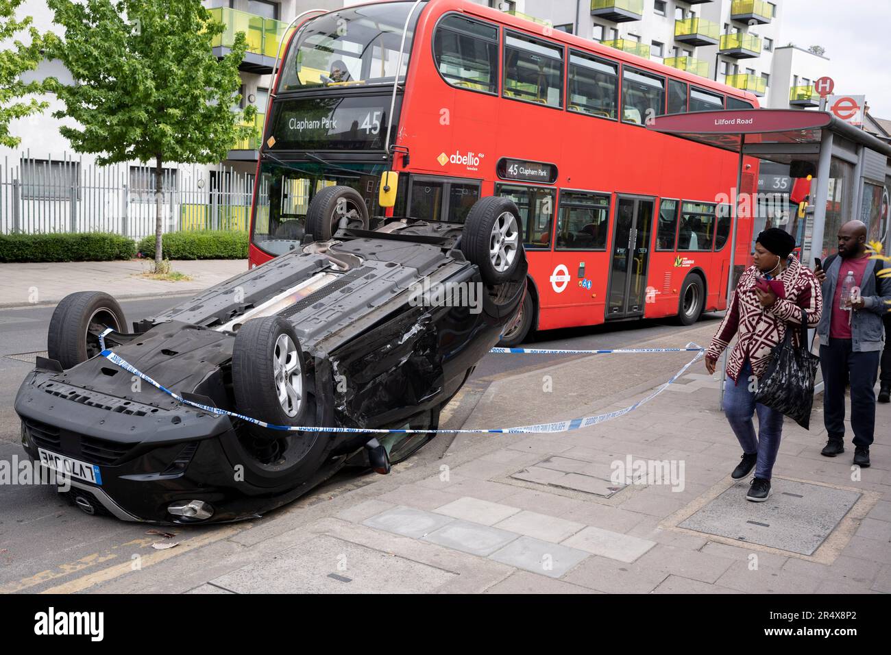 A London bus passes the aftermath of a car crash in which an overturned ...