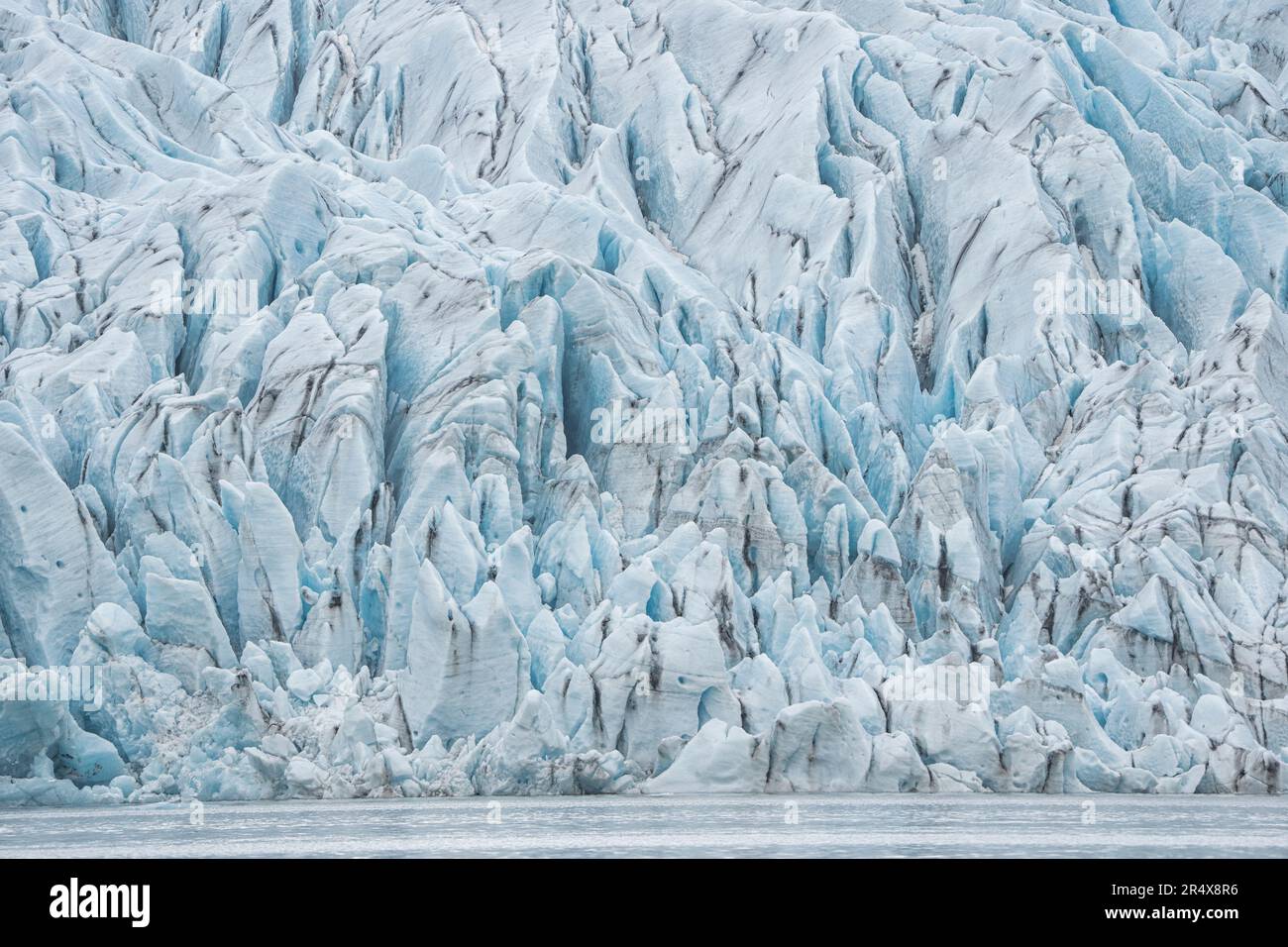 Stunning view of the silt streaked, jagged blue ice shapes of a glacier ...