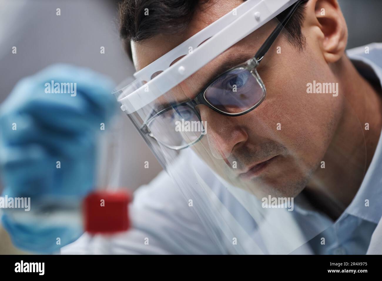 Closeup of male scientist wearing face shield in laboratory while doing ...