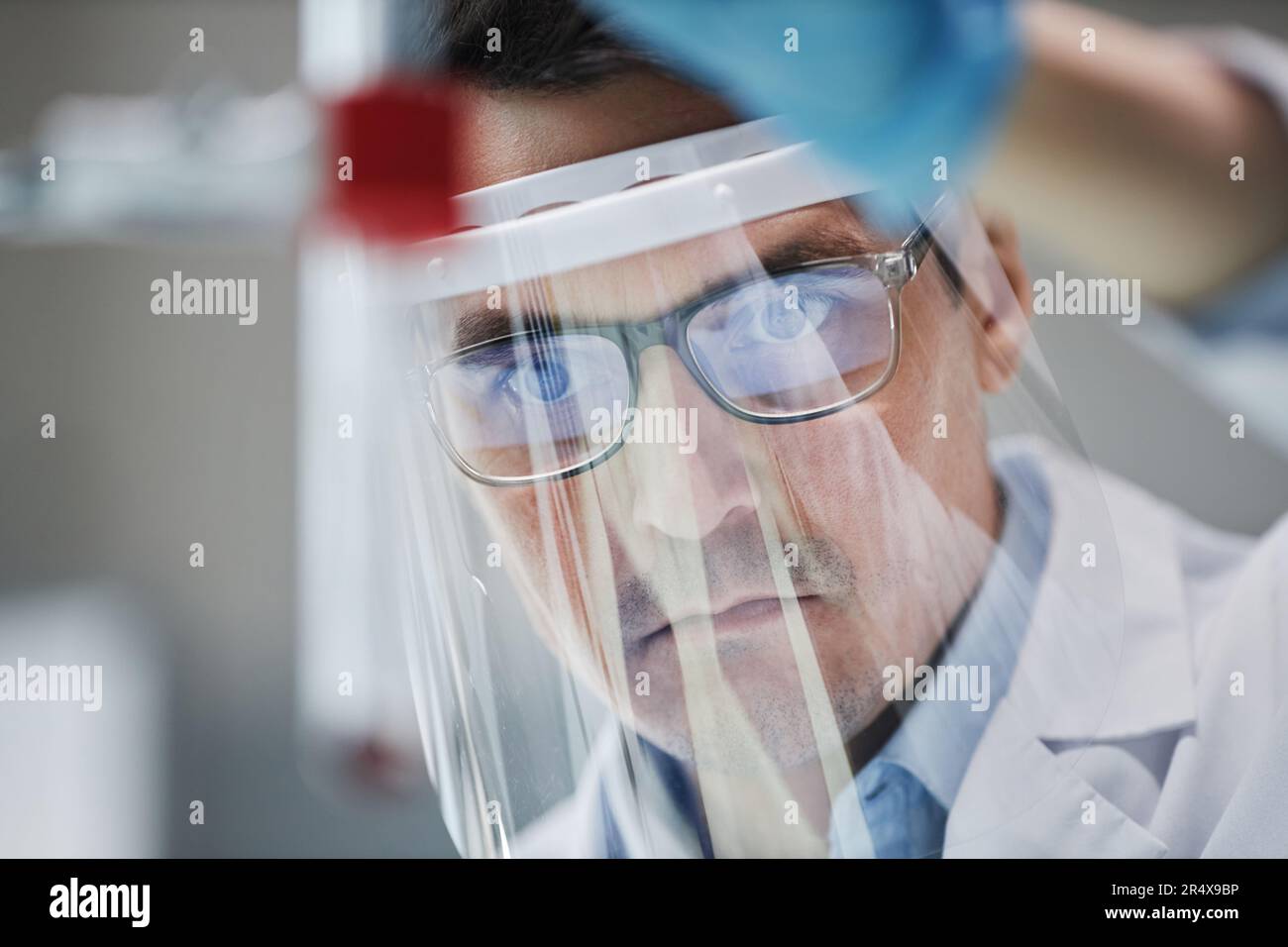 Closeup of male scientist wearing face shield in laboratory while doing ...