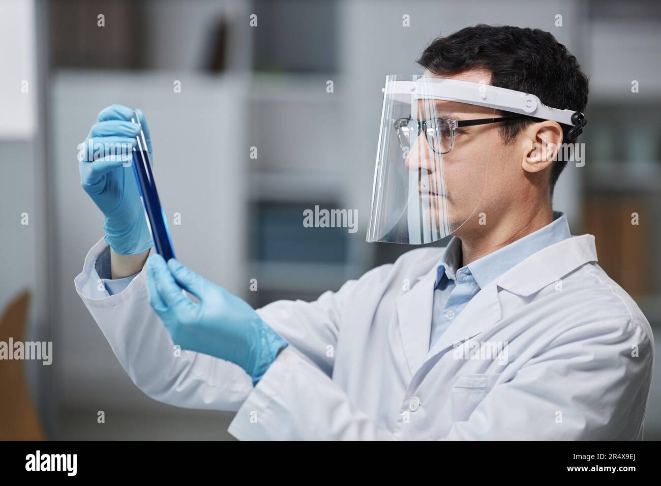 Side view portrait of male scientist wearing face shield in laboratory ...