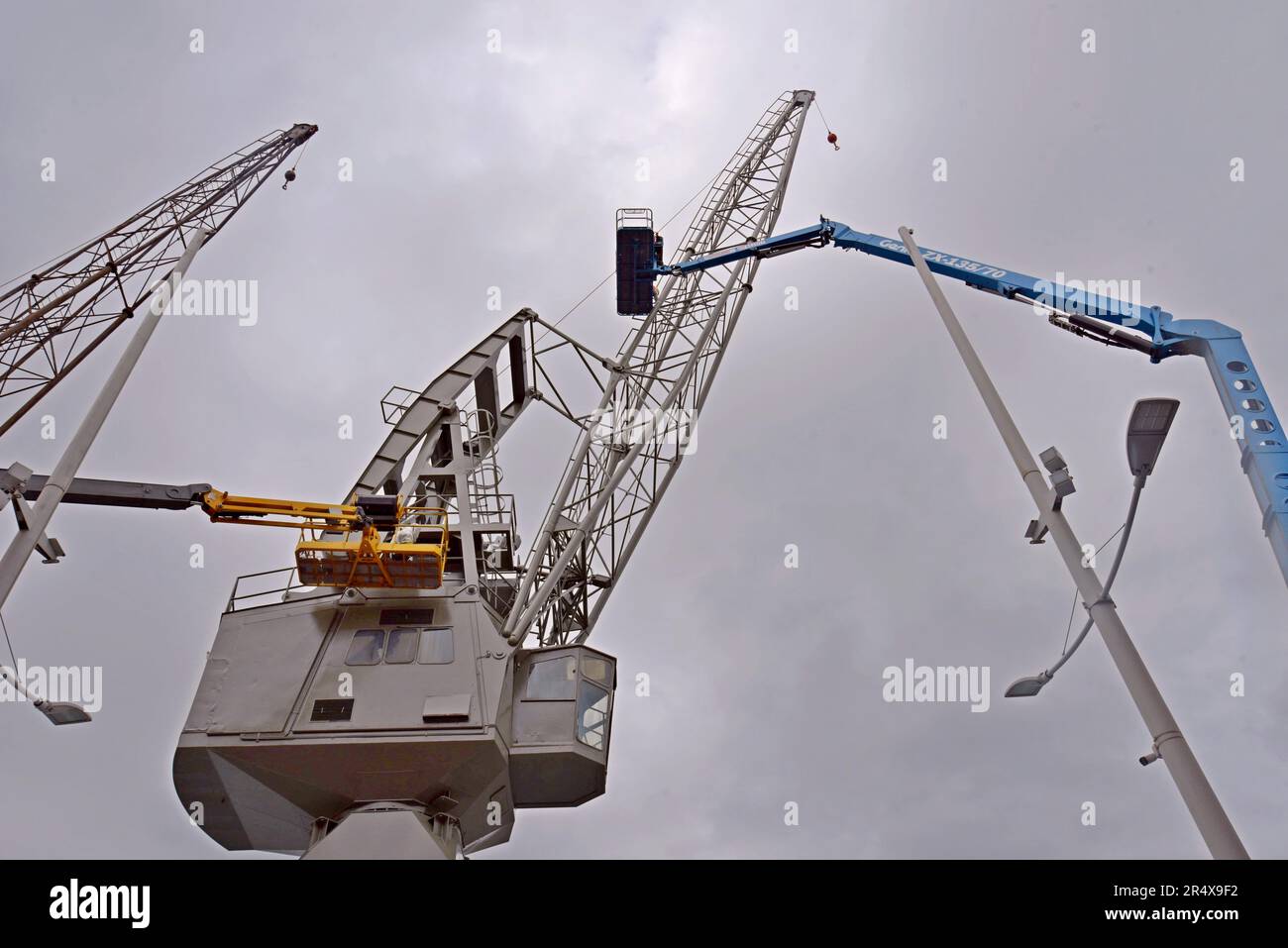People on cherry pickers restoring and painting a historic harbour ...