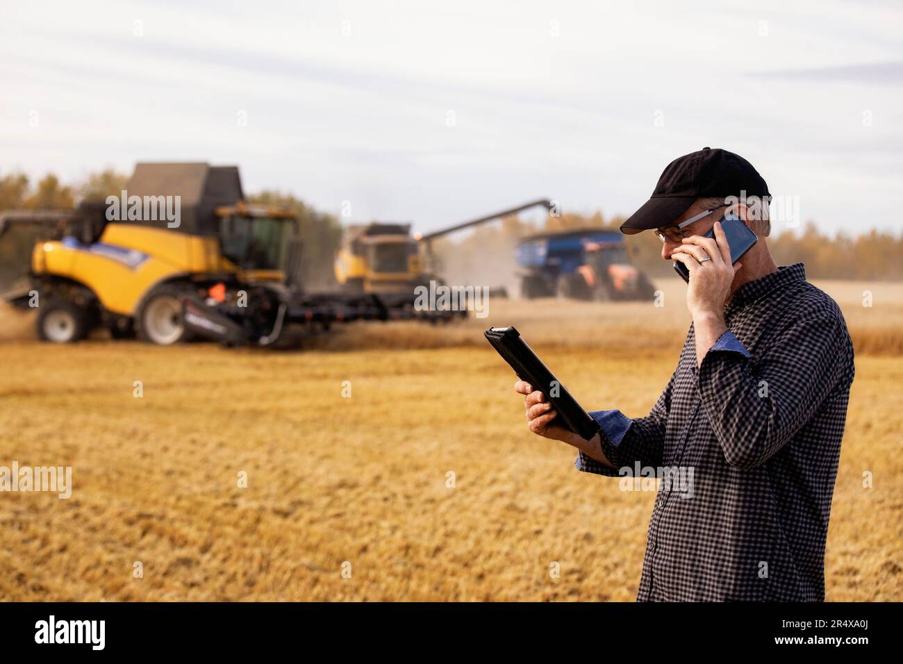Farmer using a tablet to manage his harvest and talking on his ...
