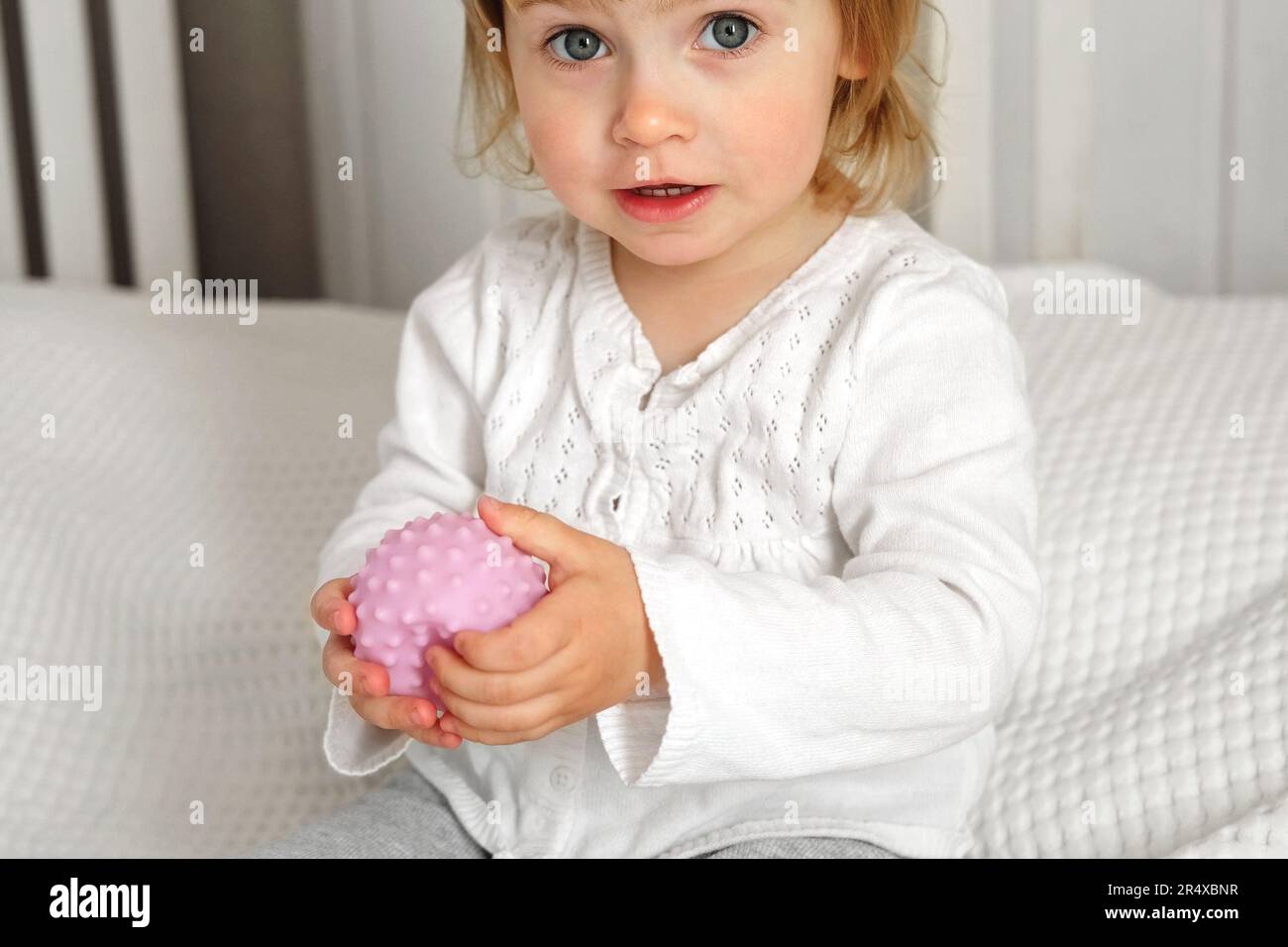Cute baby girl playing tactile knobby balls. Young child hand plays ...