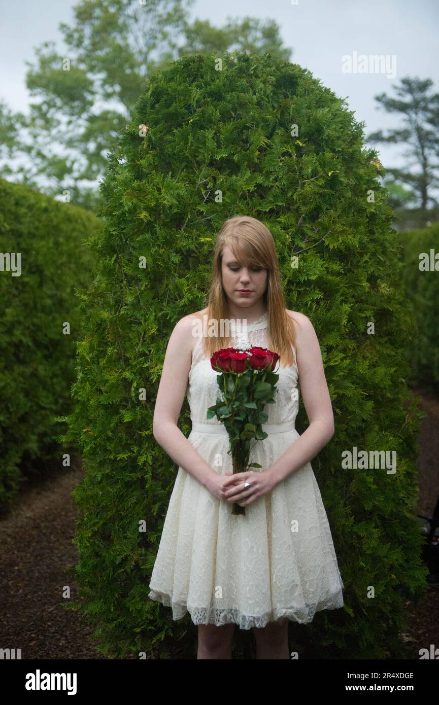 Young woman stands with bouquet of red roses in a garden area; Luray ...