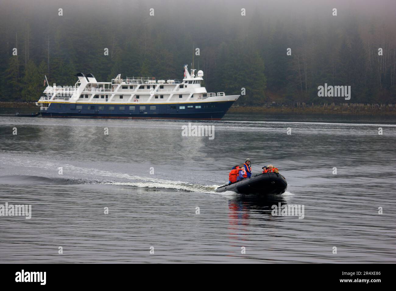 Ecotourists heading past a cruise ship in a pontoon boat in Klewnuggit ...