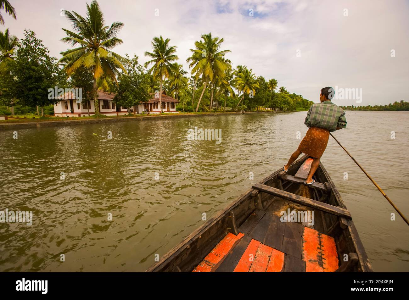 Boatman plies the backwaters past a farmstay in Kerala, India ...