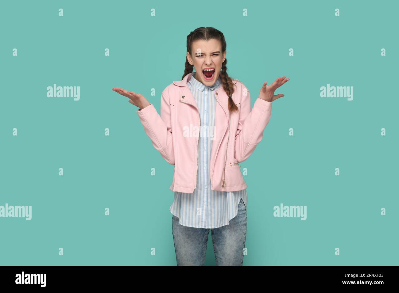 Portrait of angry aggressive teenager girl with braids wearing pink ...
